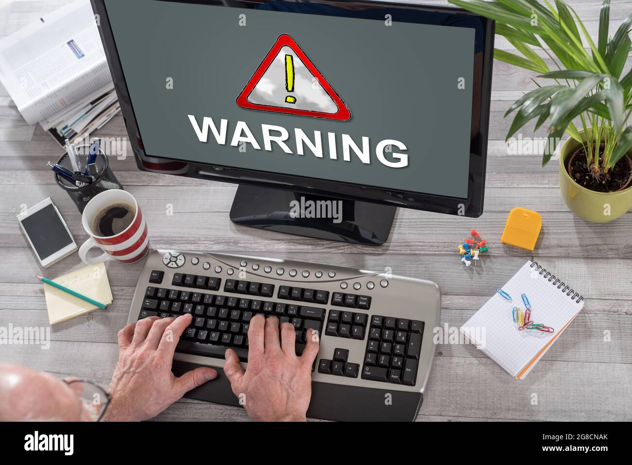 Man using a computer with warning concept on the screen Stock Photo - Alamy