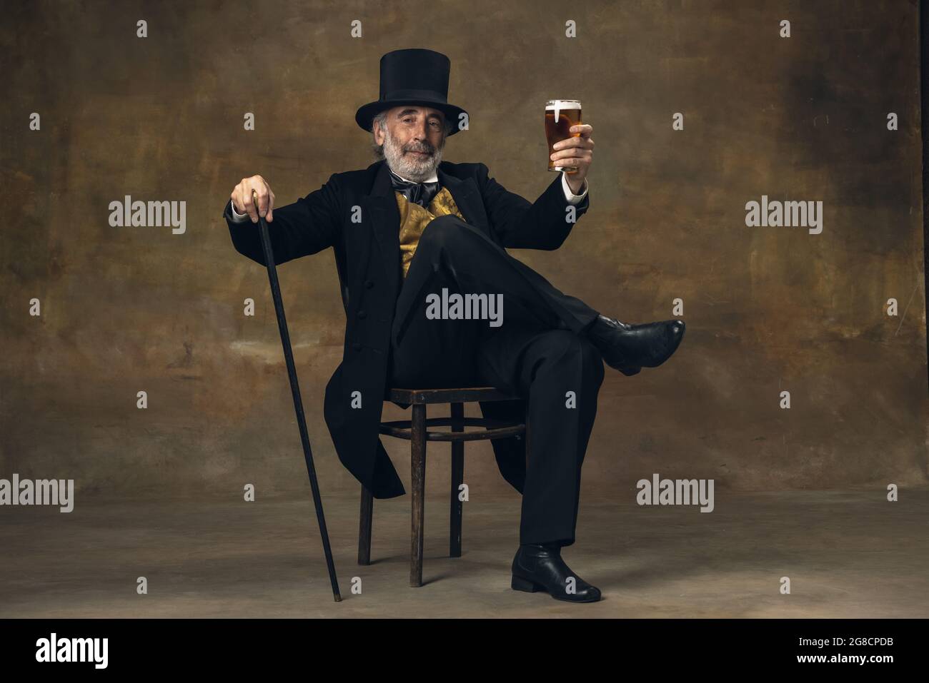Elderly gray-haired man, gentleman, aristocrat or actor drinking beer ...