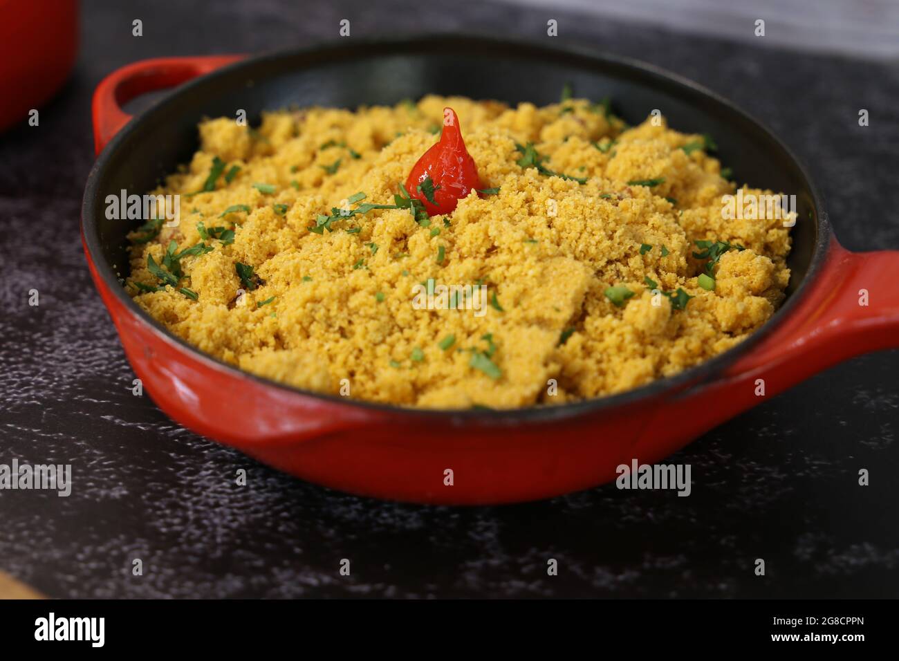 red iron pot with Farofa. Traditional Brazilian food. On a dark ...