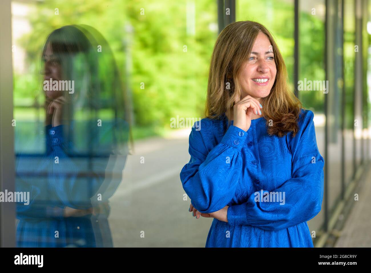 Elegant woman standing waiting reflected in a large glass window ...