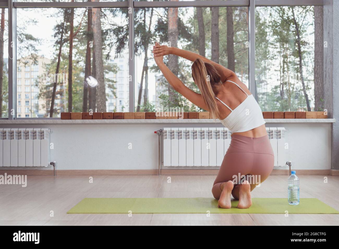 Yoga woman back view meditate sitting in lotus pose over big windows ...