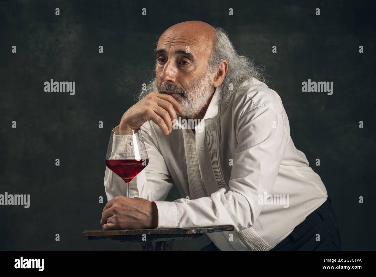 Elderly gray-haired man, medieval hystorical person, actor drinking ...