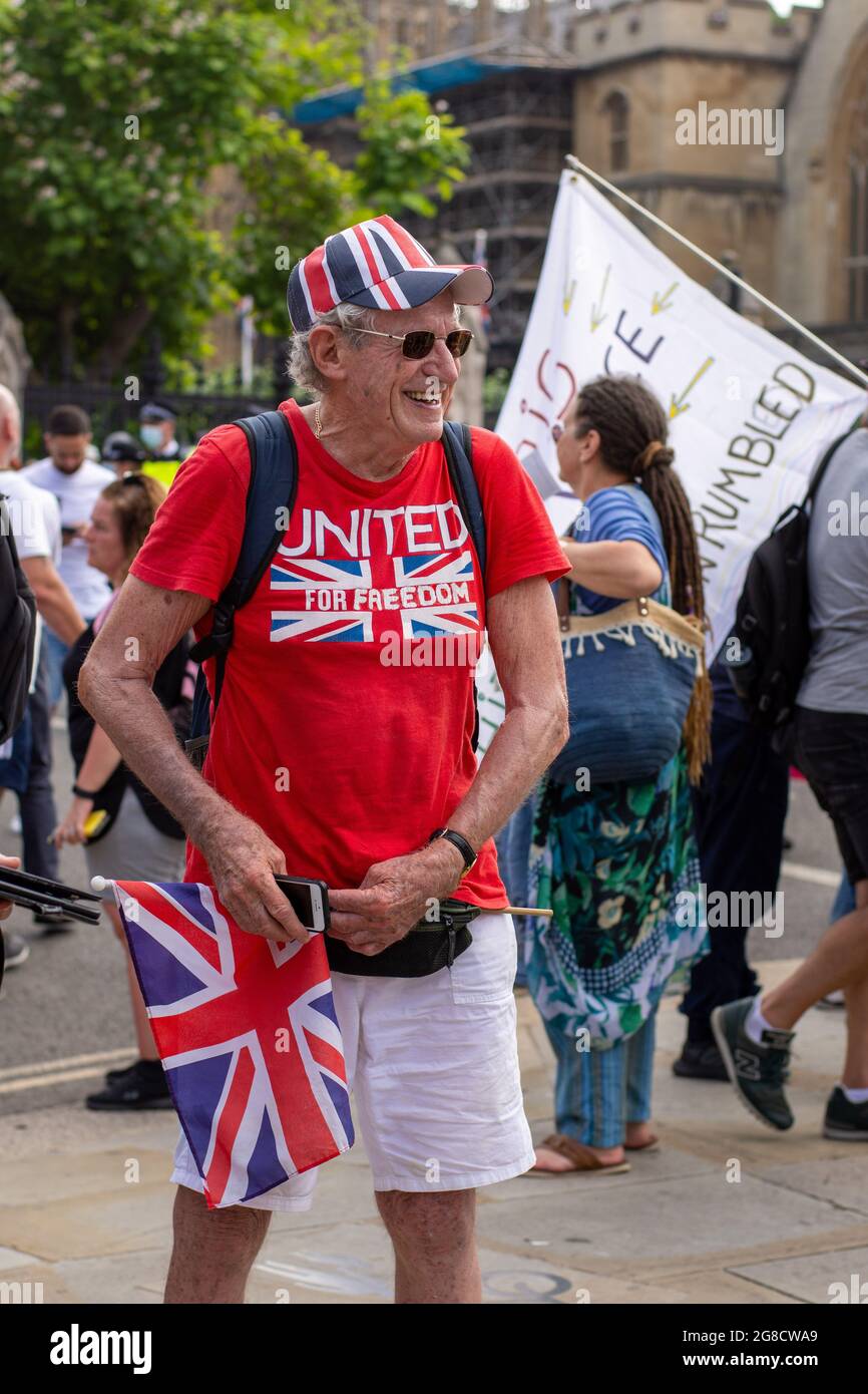London, UK. 19th July, 2021. A protester holds a Union Jack flag ...