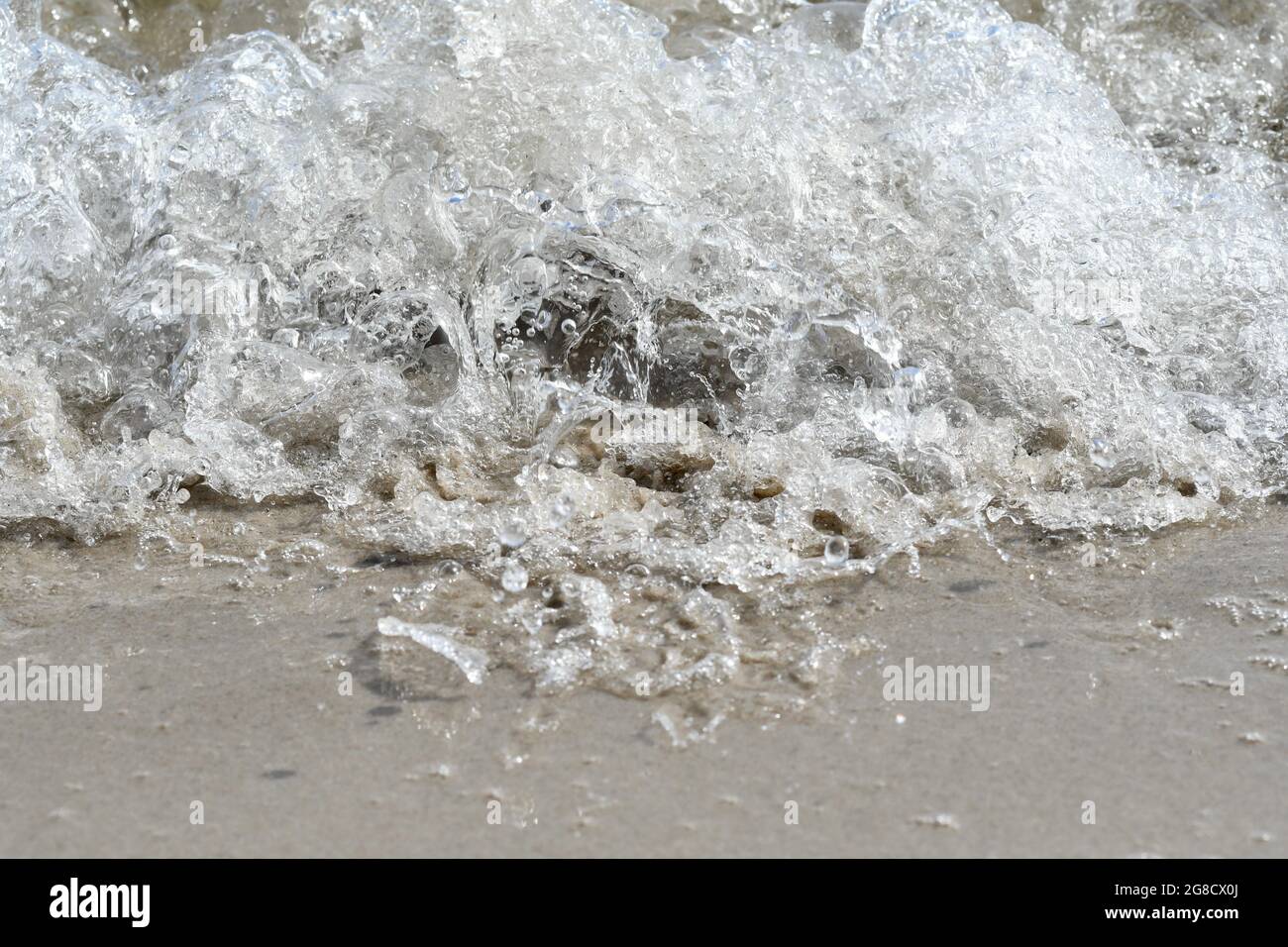 Photo of an ocean wave crashing in on shore on the beach Stock Photo ...