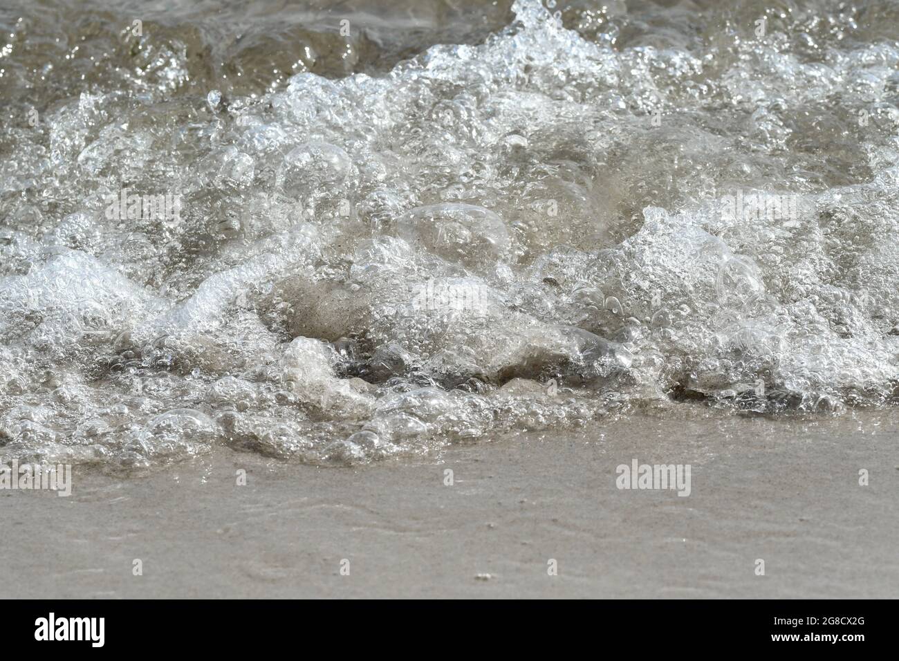 Photo of an ocean wave crashing in on shore on the beach Stock Photo ...