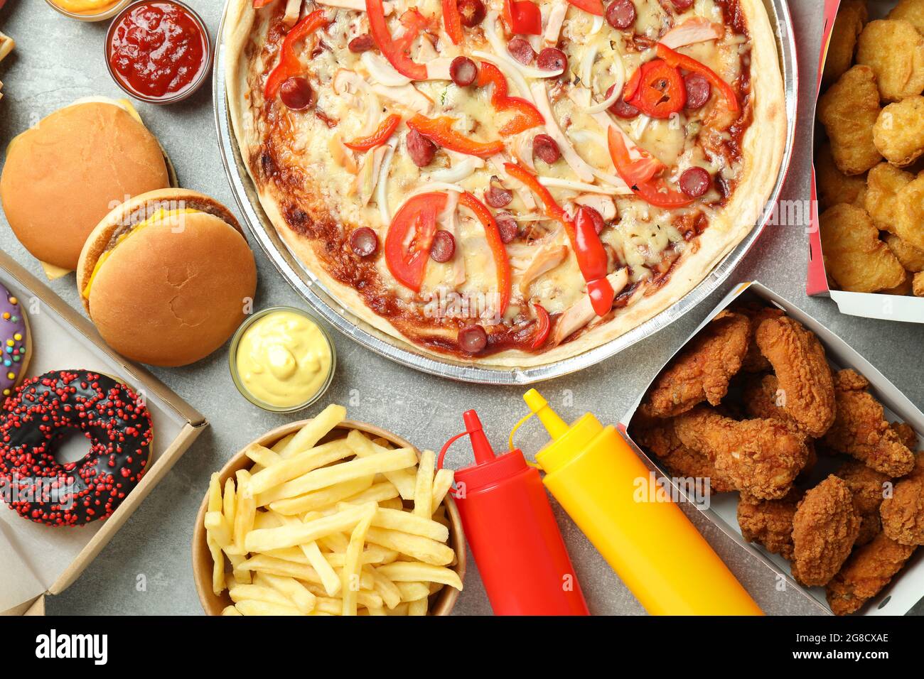 Different fast food on gray textured table Stock Photo - Alamy