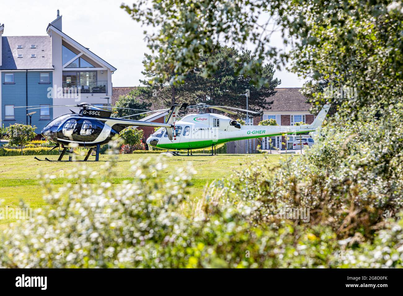 Two helicopters parked on grassland near modern houses Stock Photo - Alamy