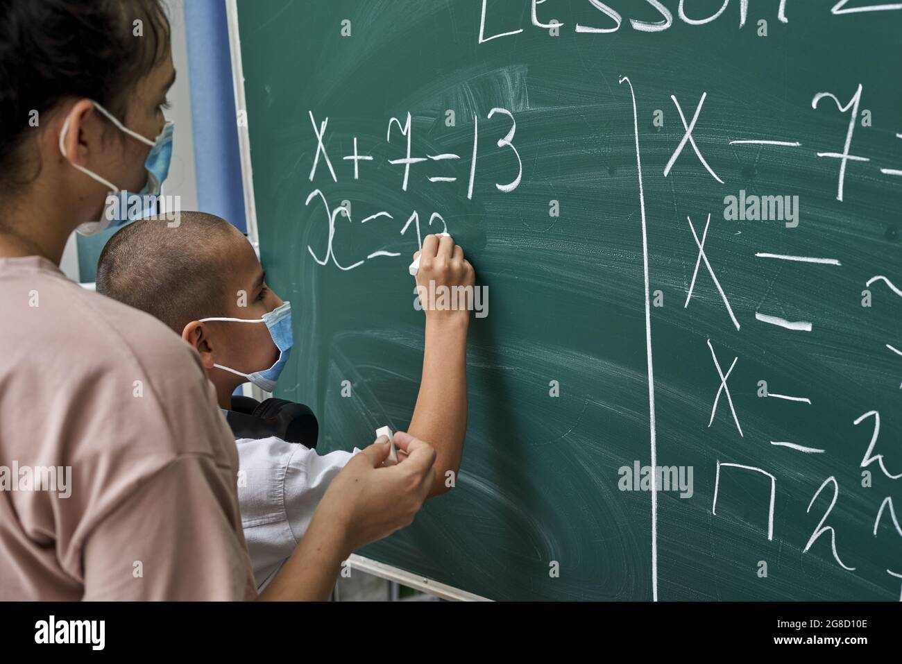 Multi-racial young female teacher helping a pupil to solve a math ...