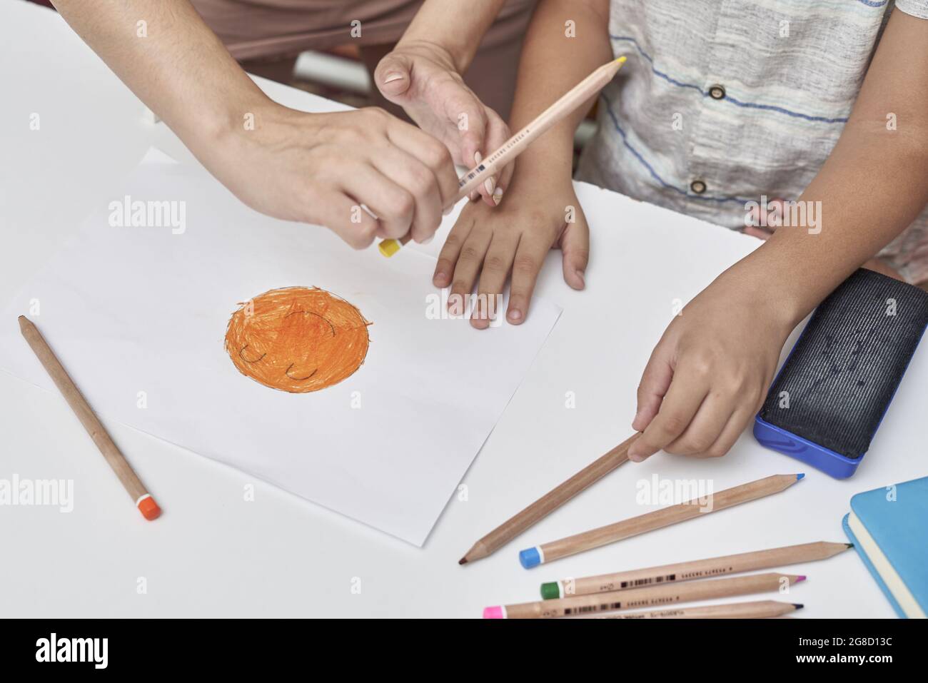 Adult art teacher helping a pupil to draw during the class at school ...