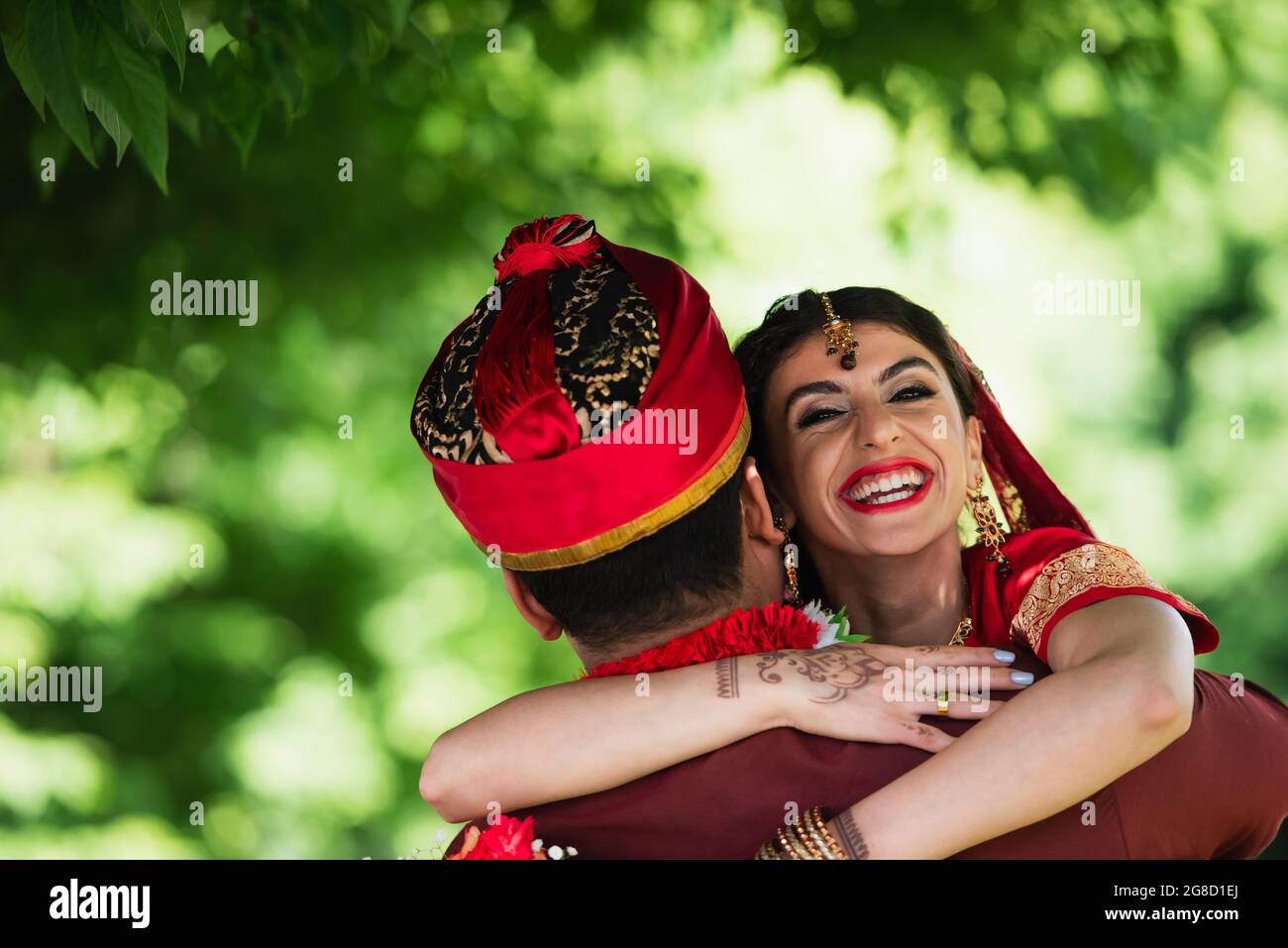 back view of indian man in turban hugging happy bride in traditional ...