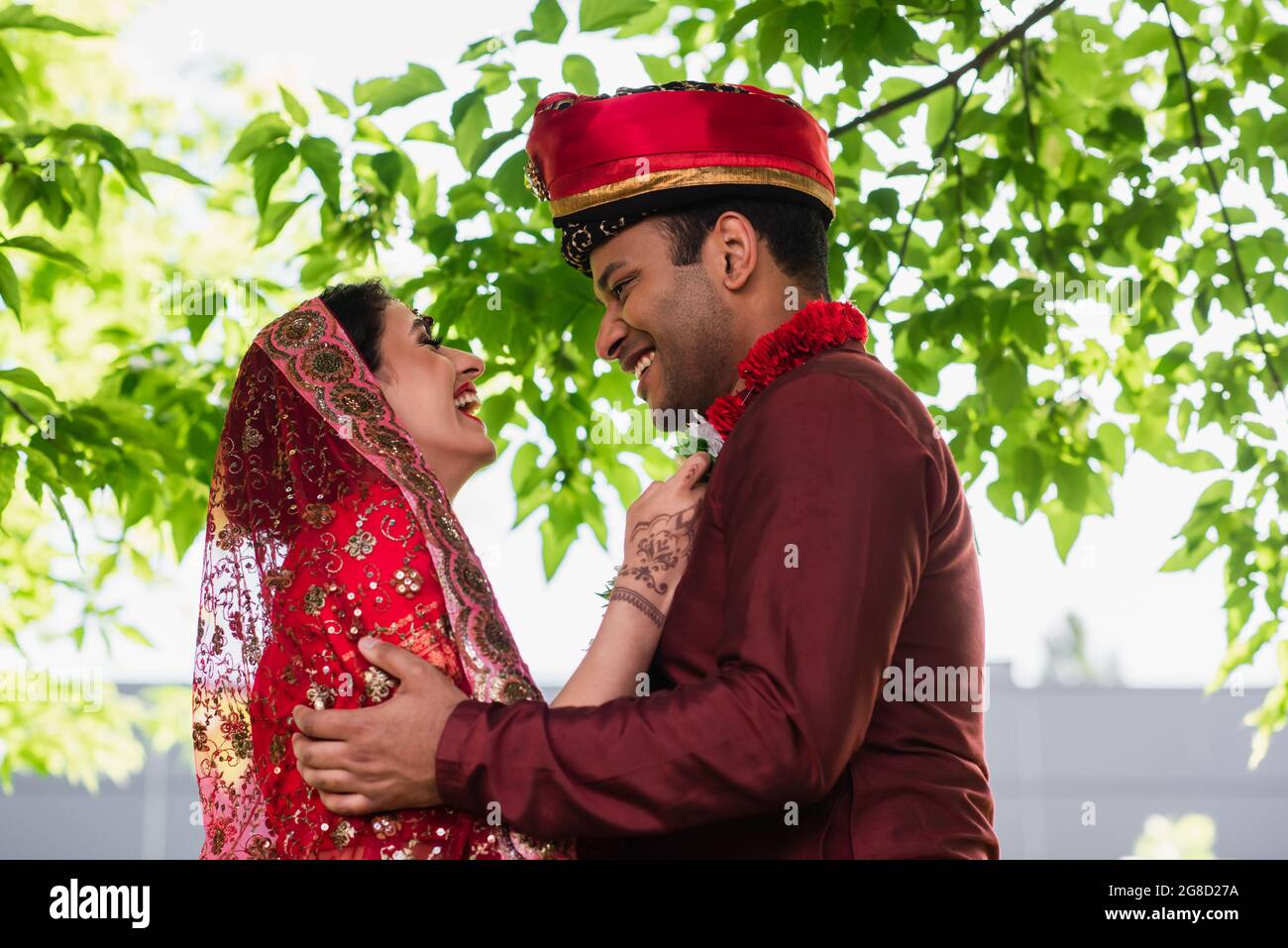 side view of cheerful indian bride wearing garland on bridegroom Stock ...