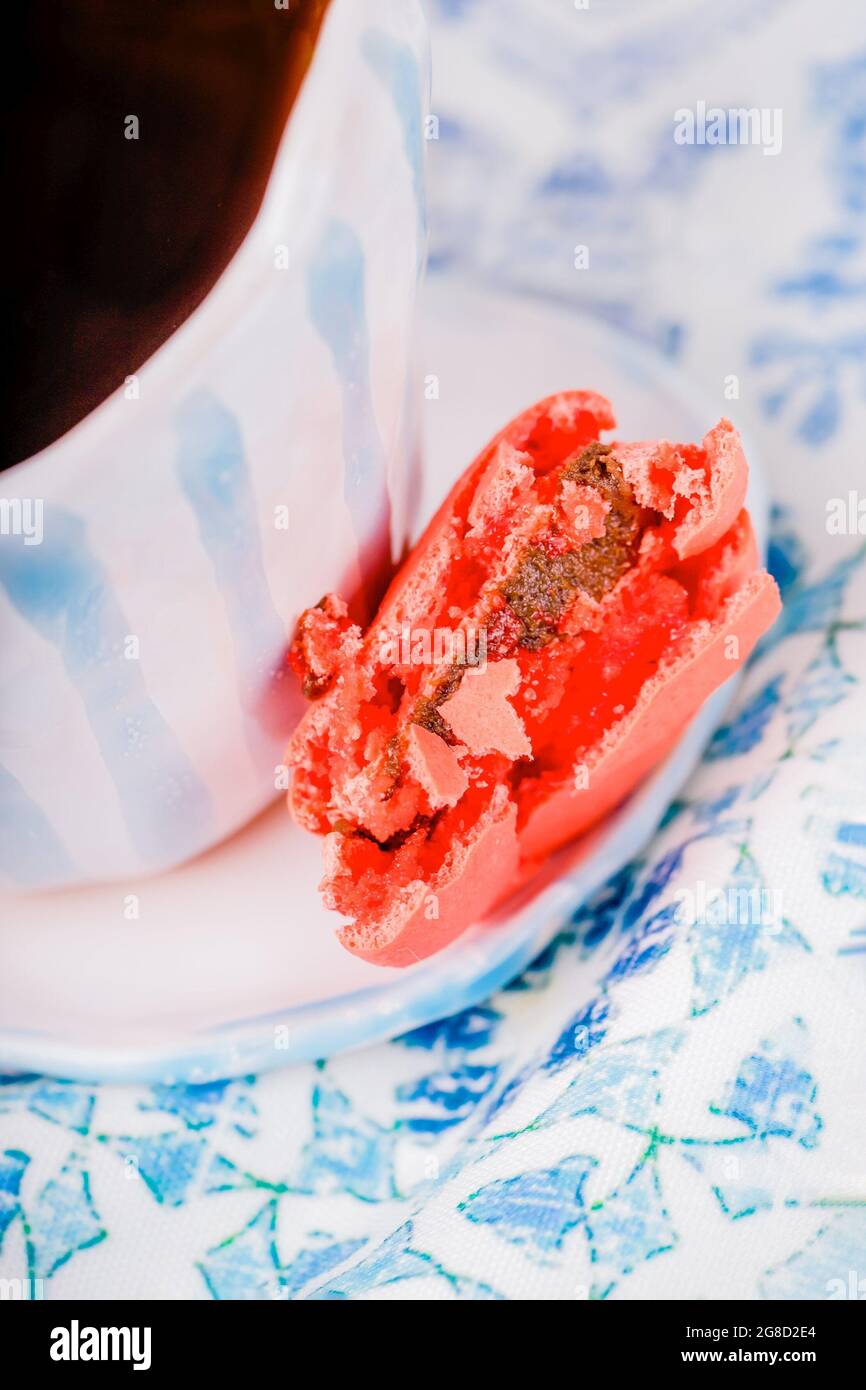 Hand made cup of coffee and bitten coral color macaroon or macaron ...