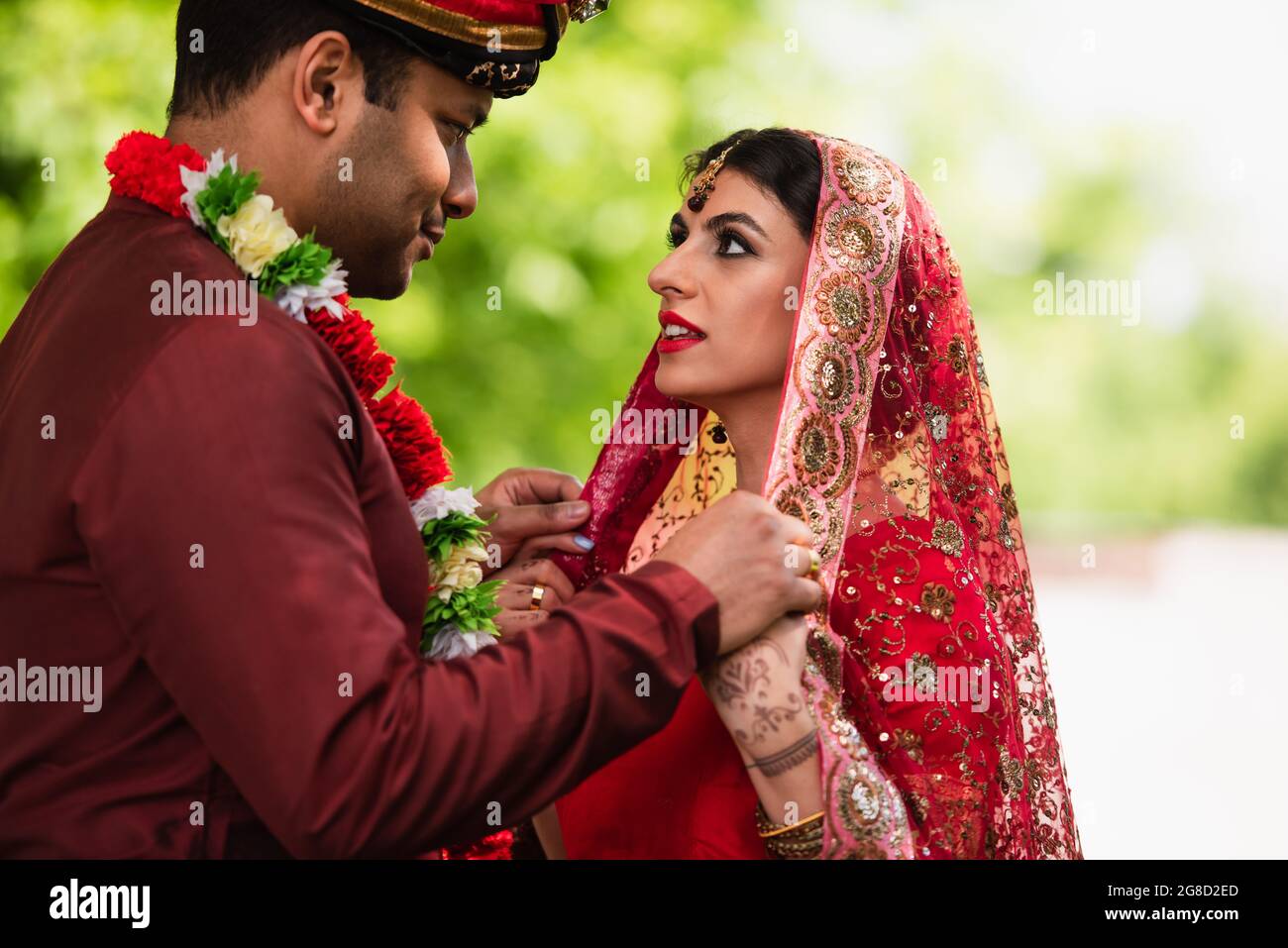 indian man adjusting headscarf on bride in sari Stock Photo - Alamy