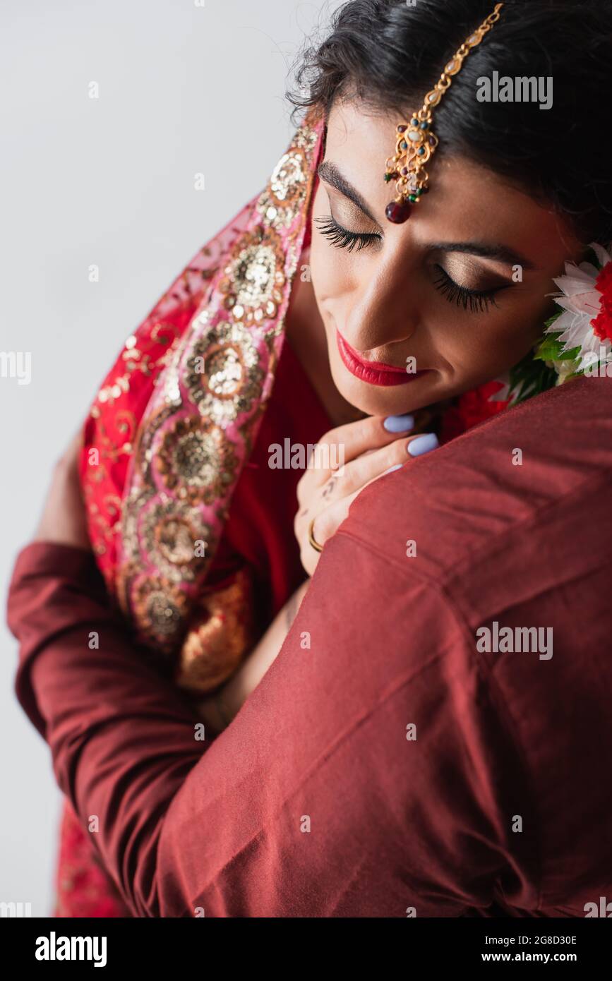 bridegroom hugging indian bride isolated on grey Stock Photo - Alamy