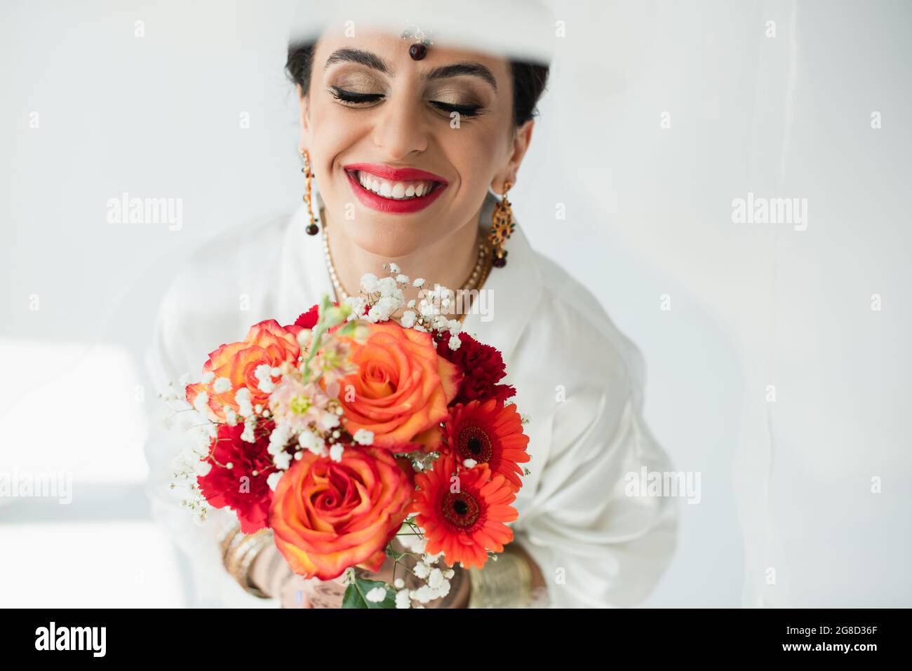 young happy indian bride with mehndi holding bouquet of flowers on ...