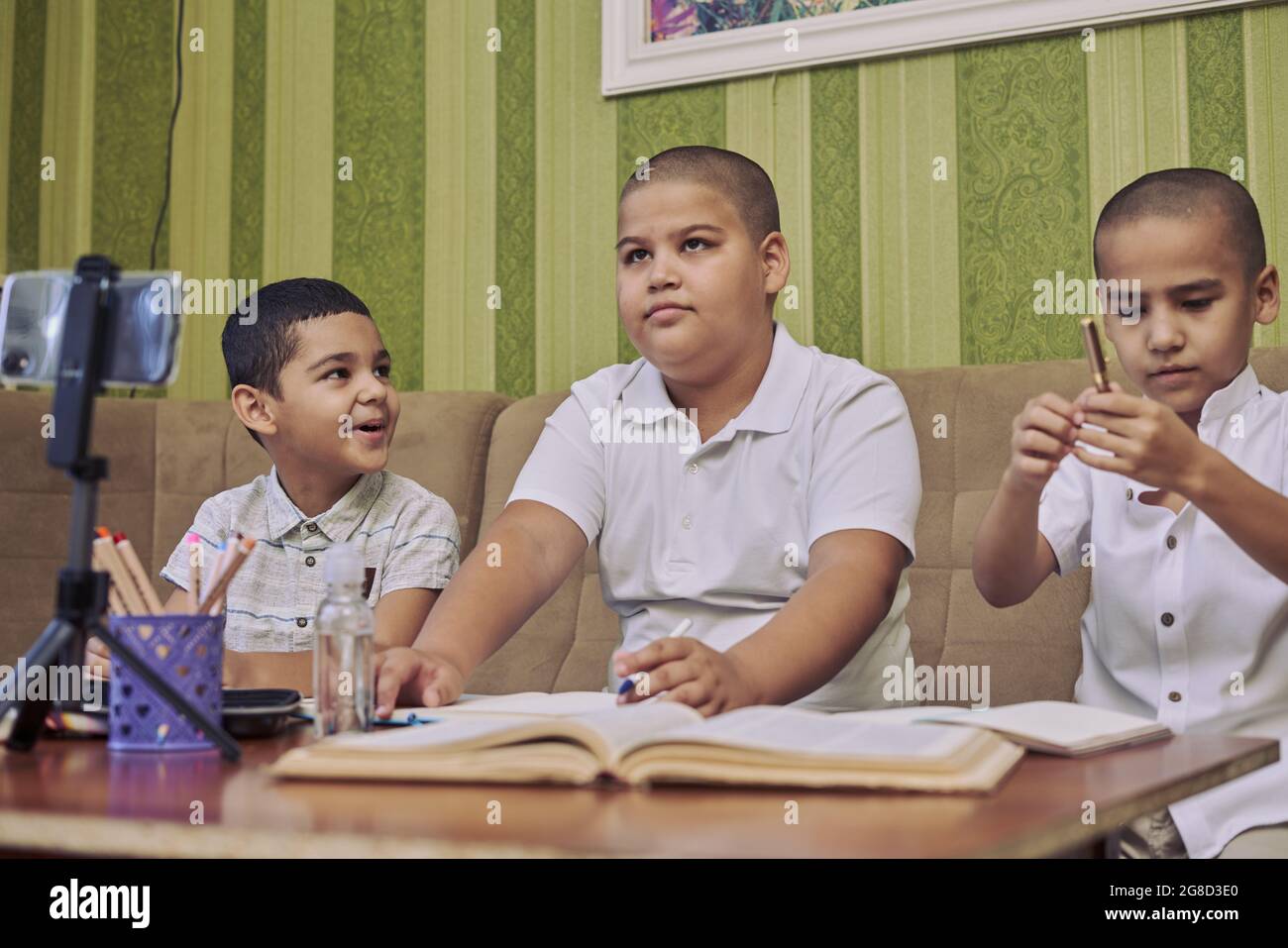 Young male pupils listening to an online class at home - concept of ...