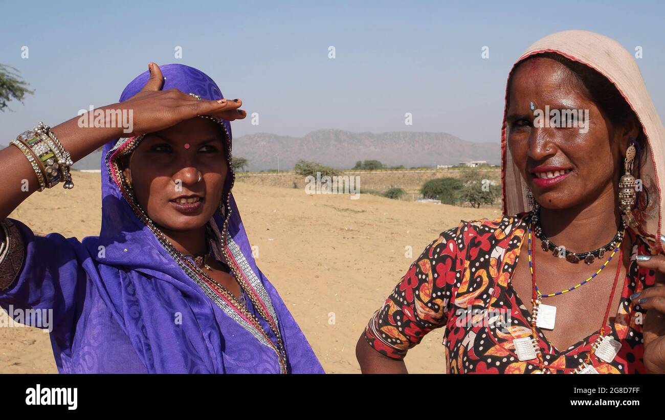 Young Indian females with colorful kerchiefs in a desert under a blue ...