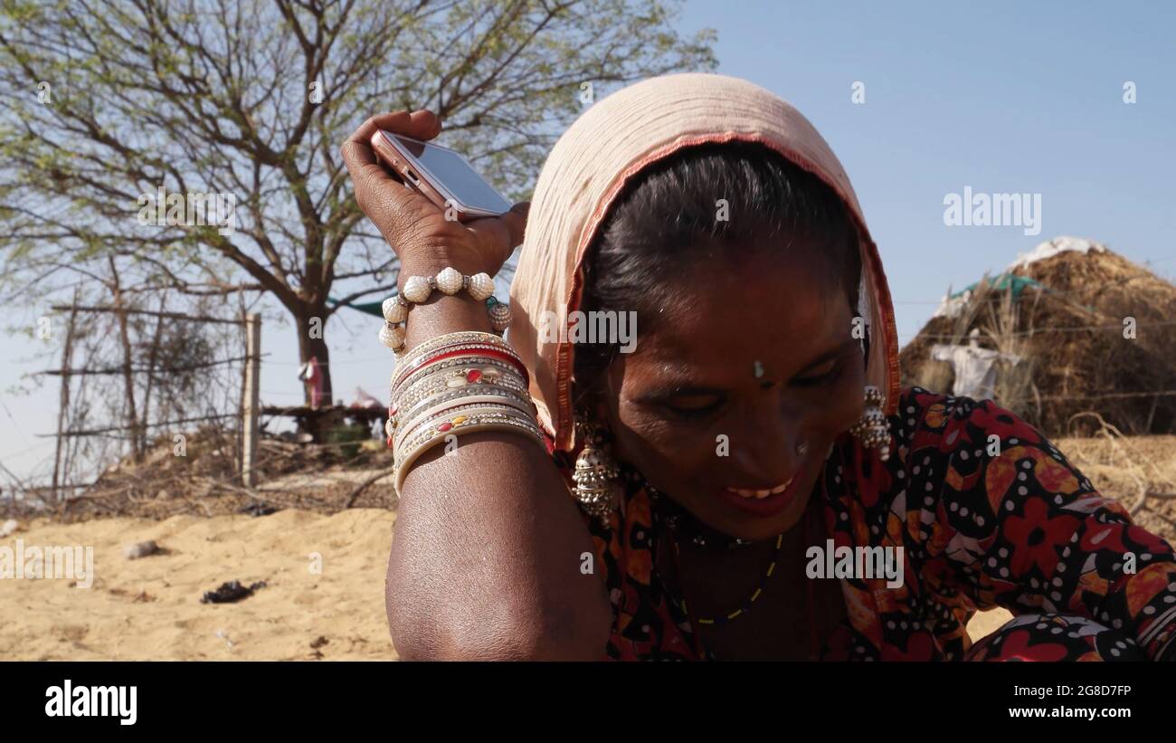 Happy young Indian female with a kerchief holding a smartphone sitting ...