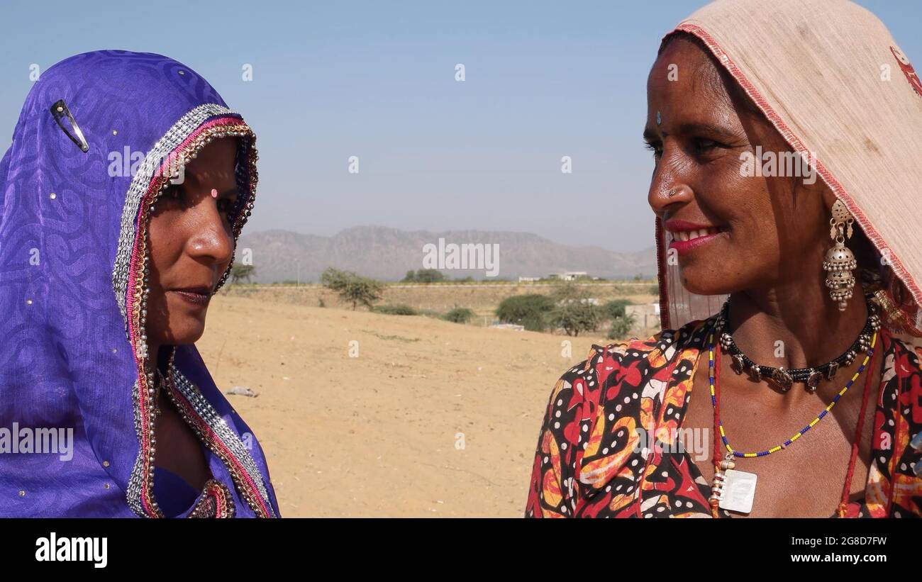 Young Indian females with colorful kerchiefs in a desert under a blue ...