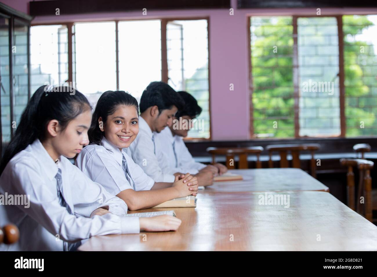 Front facing portrait of young female's student in library with ...