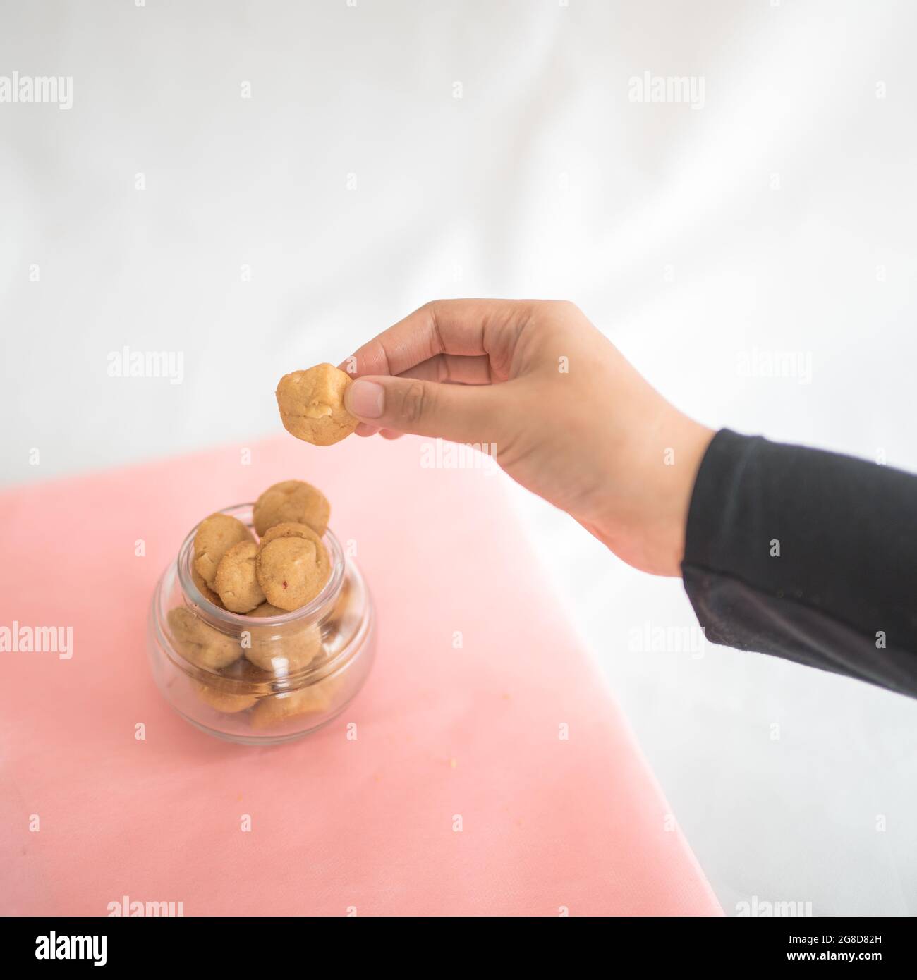 Hand picking an almond cookies from a jar Stock Photo - Alamy