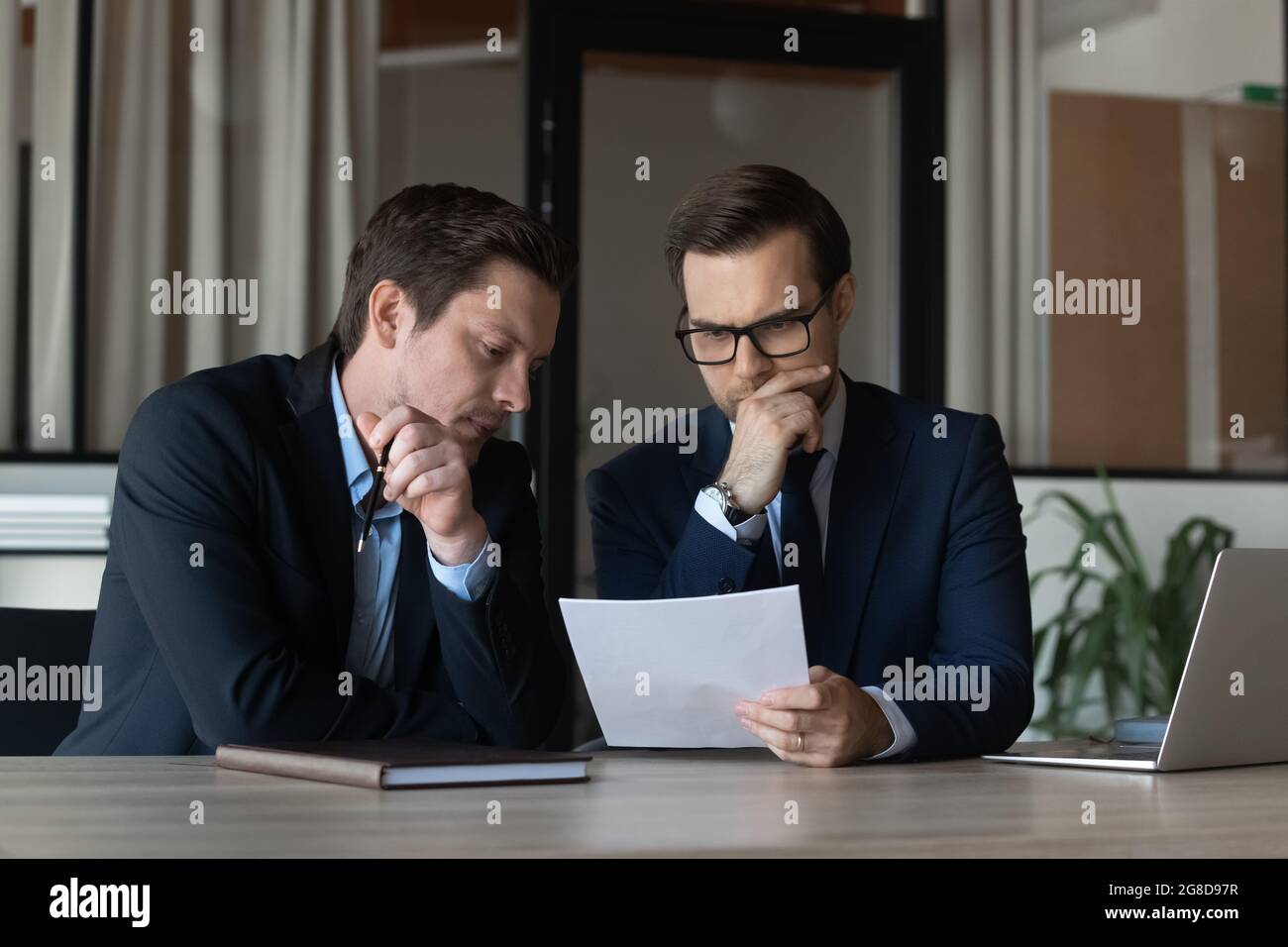 Two serious businessmen, focused business partners, coworkers reading ...