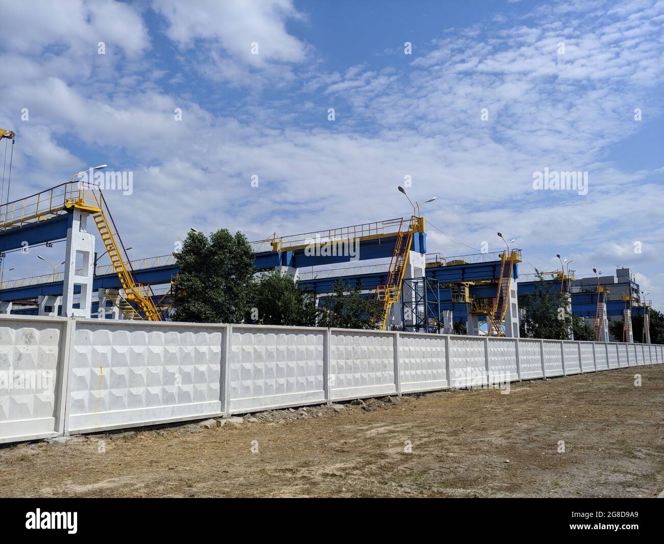 rows of industrial cargo cranes behind white fence. automatic storage ...