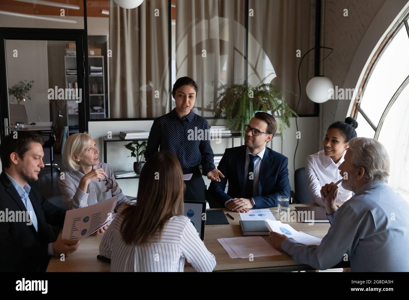 Female Indian business leader talking to diverse team, discussing ...