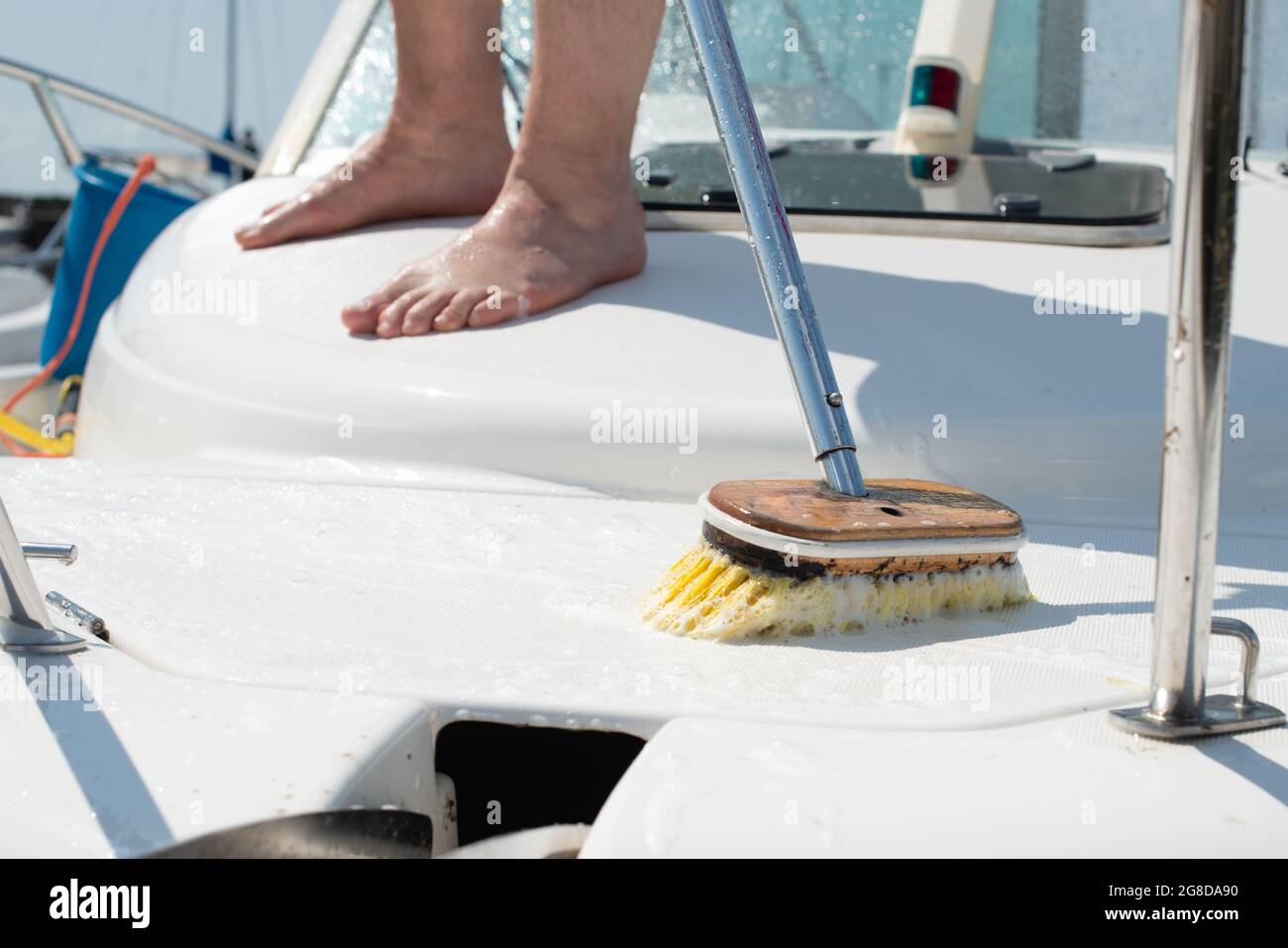 Man washing white boat with brush and pressure water system at pier ...