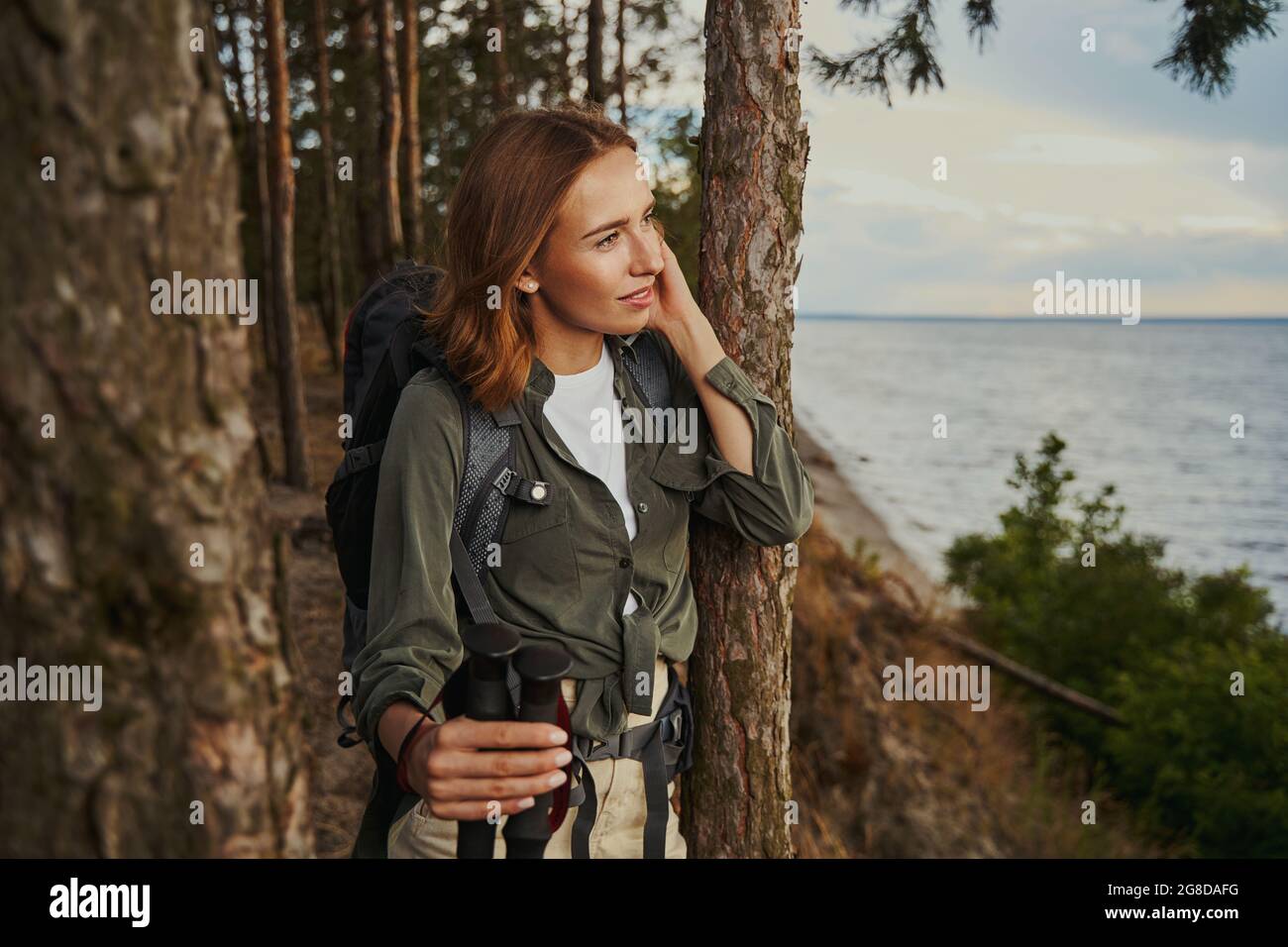 Female leaning against the tree and admiring view Stock Photo - Alamy
