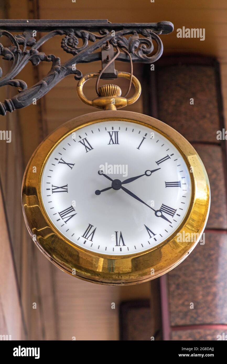 Gold Clock With Illuminated White Dial Hanging Stock Photo - Alamy