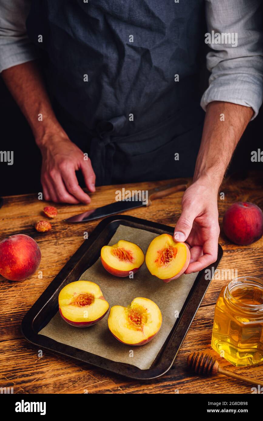 Roast halves of ripe peaches with honey. Chef puts fruits on baking ...