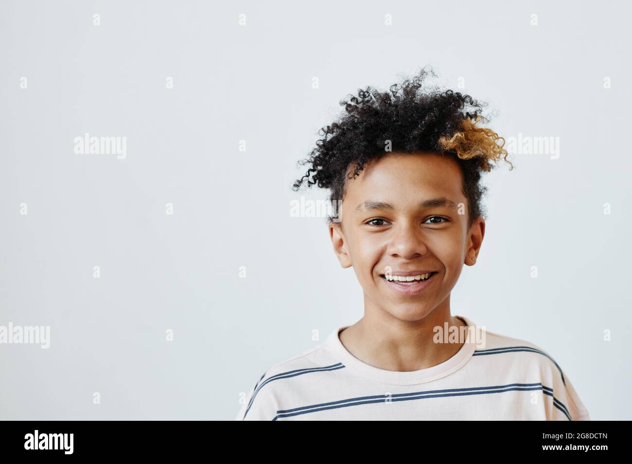 Minimal portrait of mixed-race teenage boy smiling at camera against ...