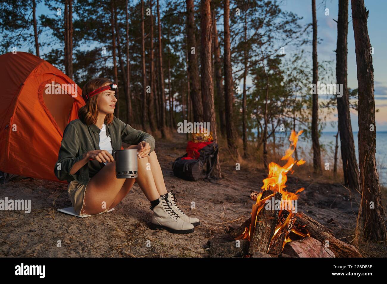 Young person sitting outside campfire hi-res stock photography and ...