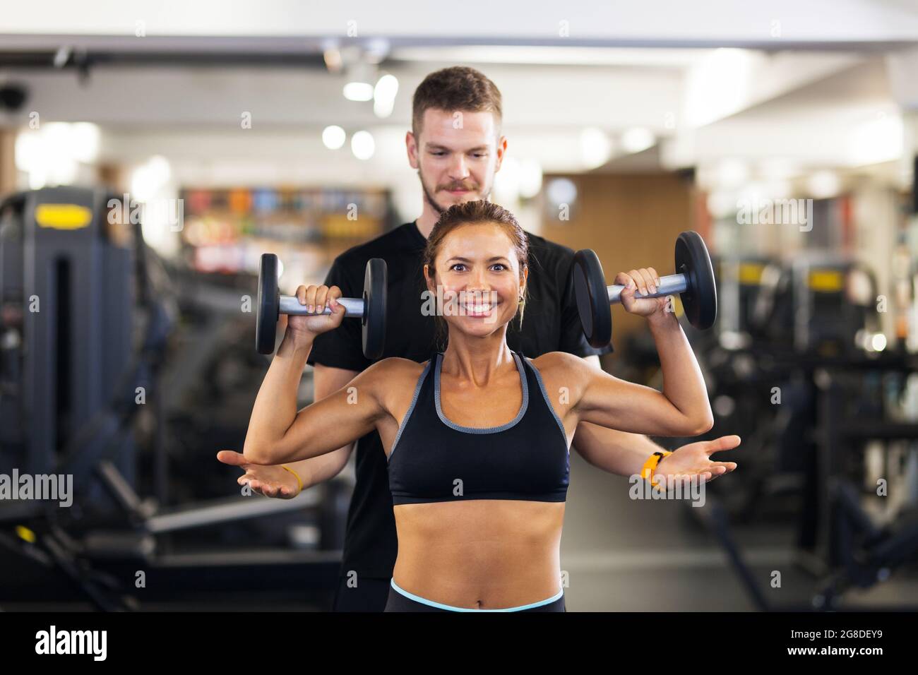 happy girl with fitness coach lifting weights Stock Photo - Alamy