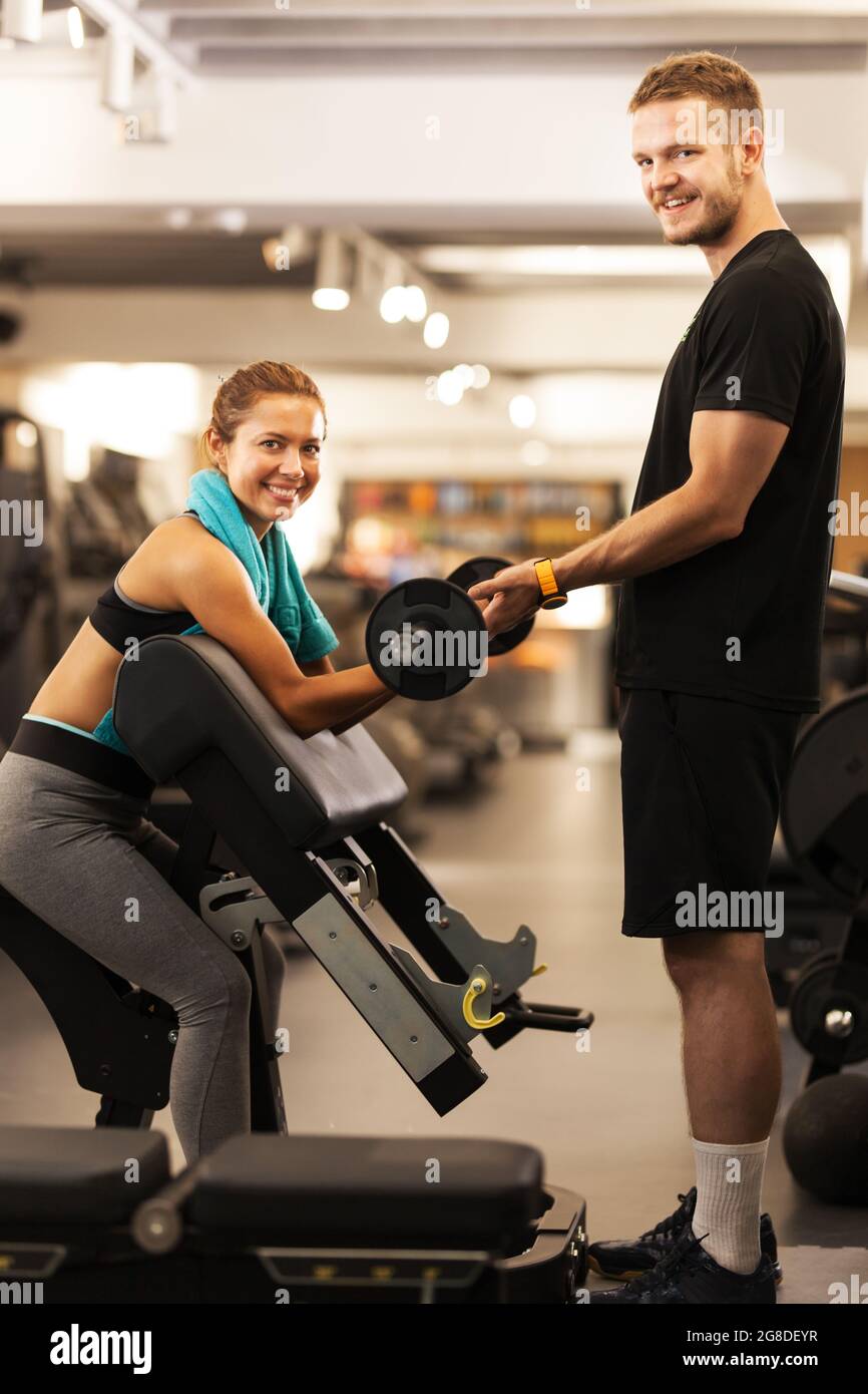 happy girl with fitness coach lifting weights Stock Photo - Alamy