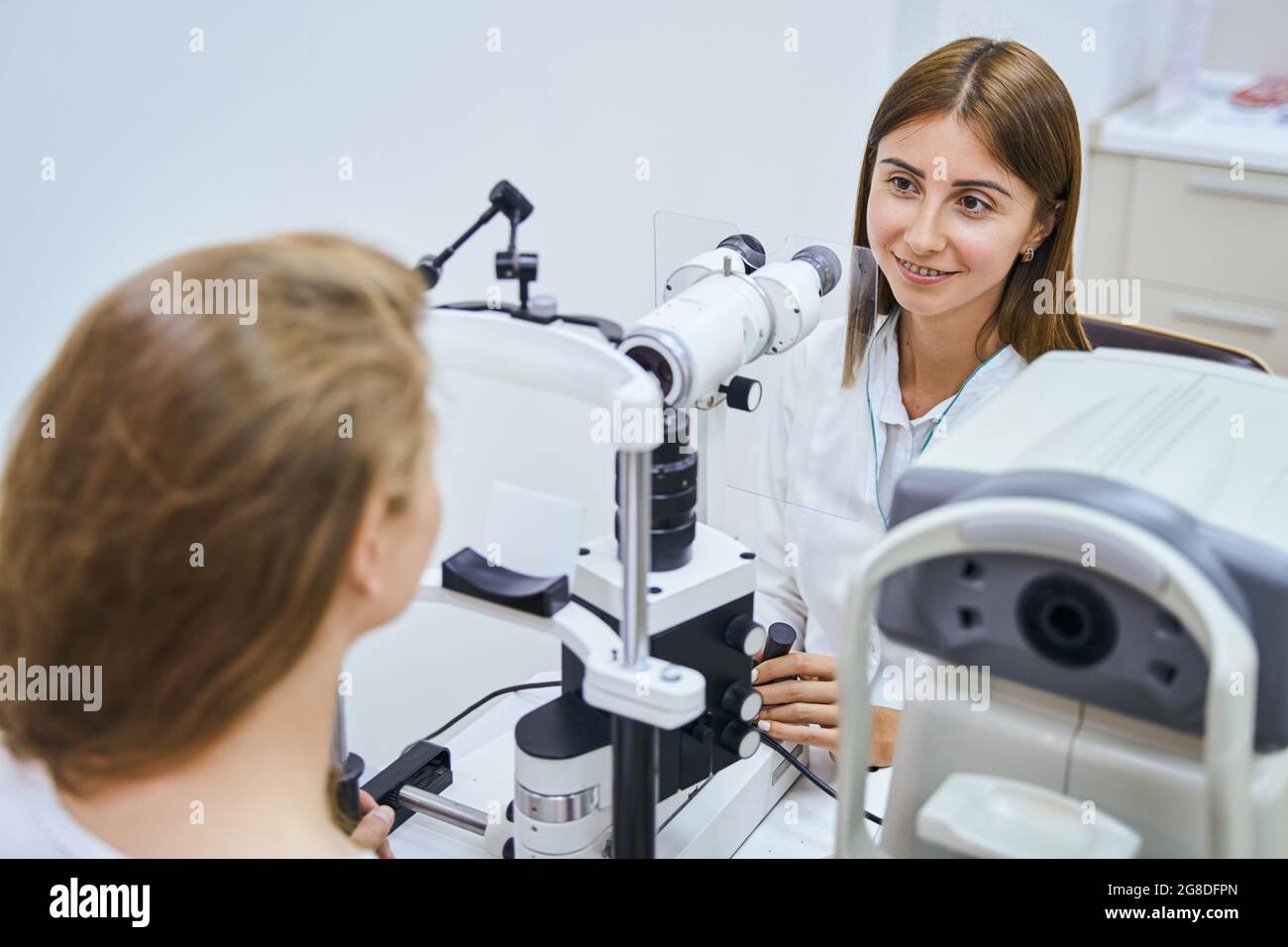 Charming doctor examining woman eyes with ophthalmic equipment Stock ...