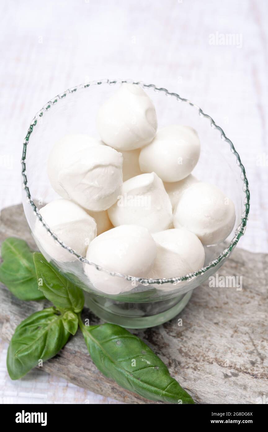Fresh white soft mini mozzarella balls served with fresh green basil ...