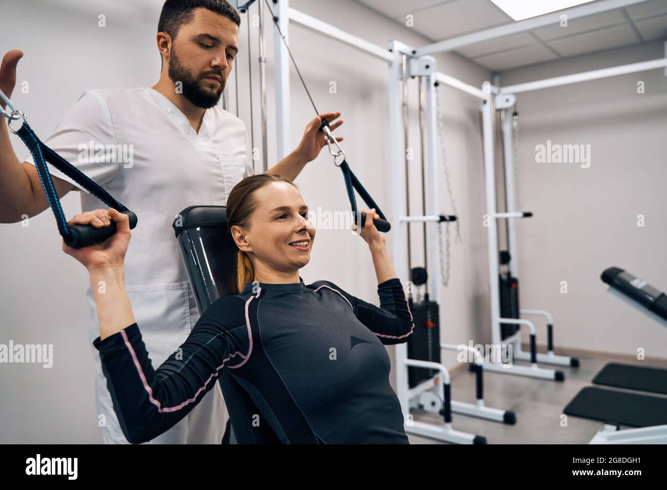 Kinesiologist assists young woman to do exercises to treat hand muscles ...