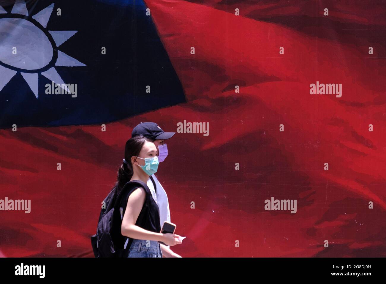Women wearing face masks walk past a Taiwanese flag ahead of the COVID ...
