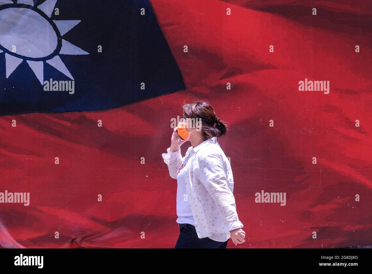 Taipei, Taiwan. 19th July, 2021. A woman wearing a face mask walks past ...