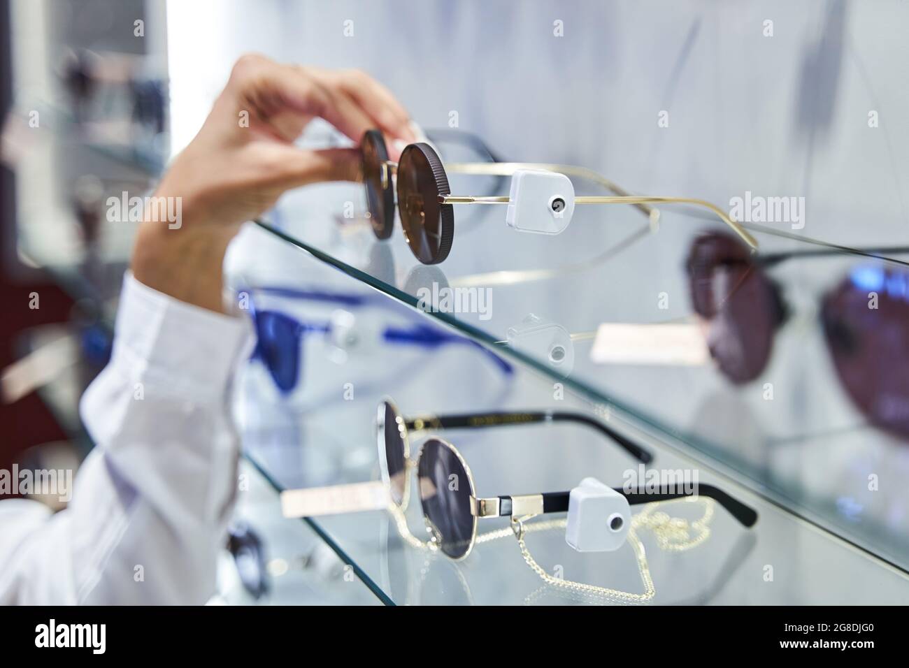 Female hand taking sunglasses from shelf in optical store Stock Photo ...