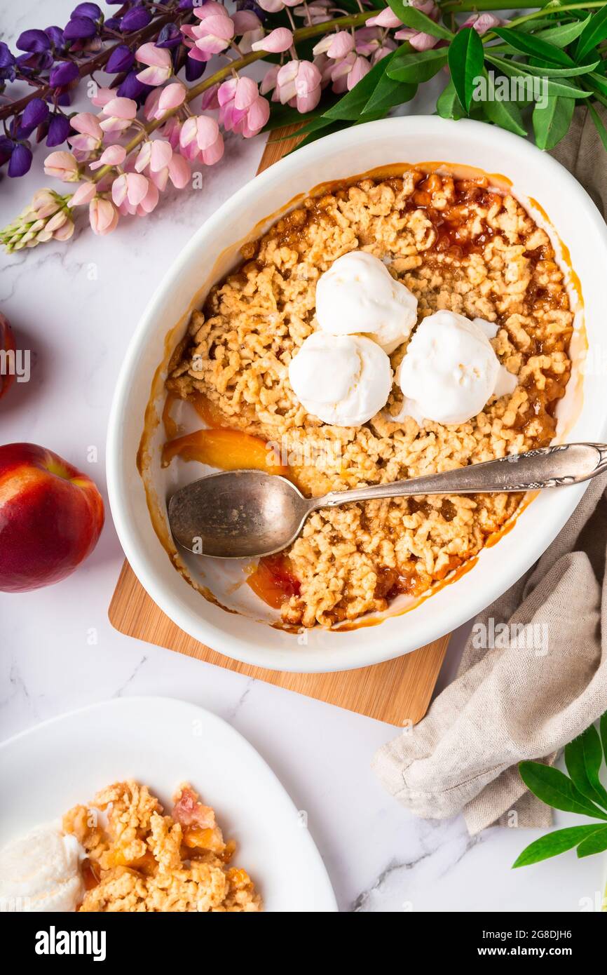 Fresh homemade nectarine crumble with vanilla ice cream in ceramic form ...