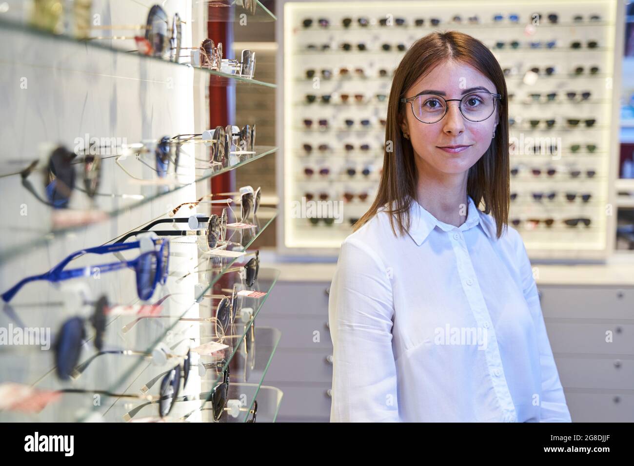 Beautiful young woman in glasses standing in optical store Stock Photo ...