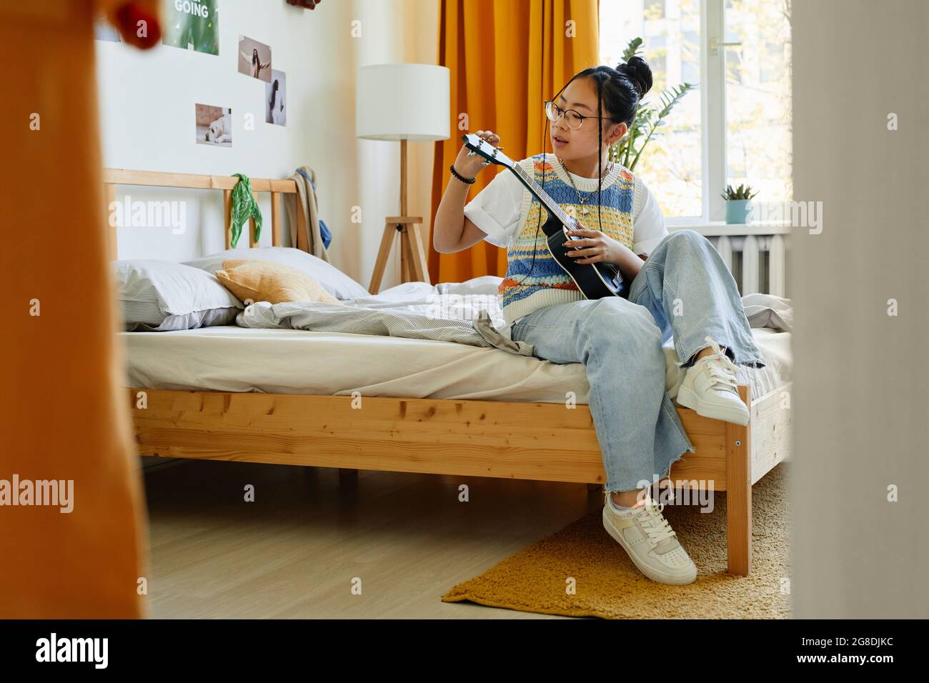 Full length portrait of trendy teenage girl playing ukulele while ...