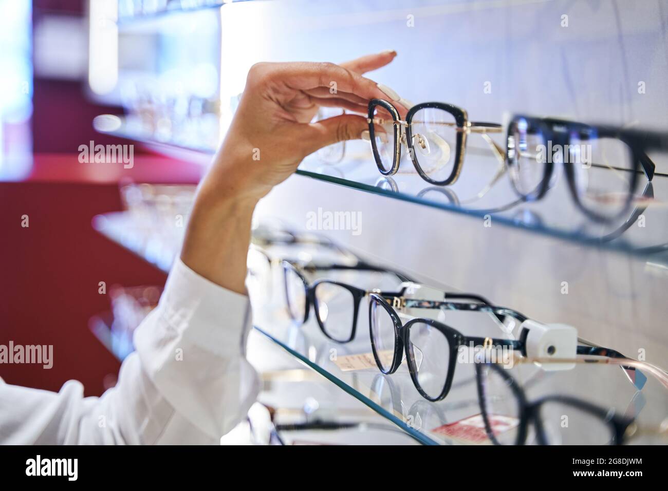 Female hand taking eyeglasses from shelf in optical store Stock Photo ...