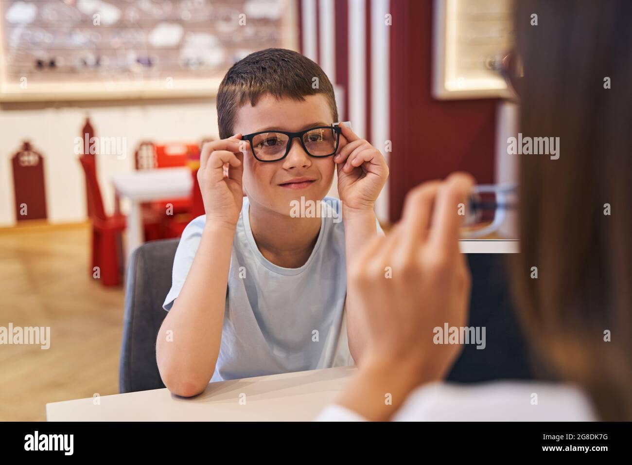 Adorable boy in glasses talking with optician in optical shop Stock ...