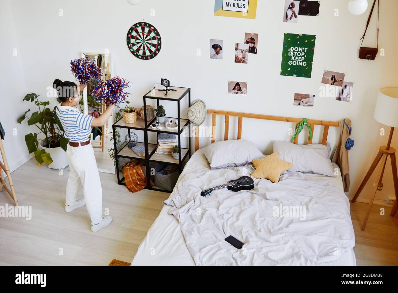 Wide angle view at teenage room interior with girl dancing holding pom ...