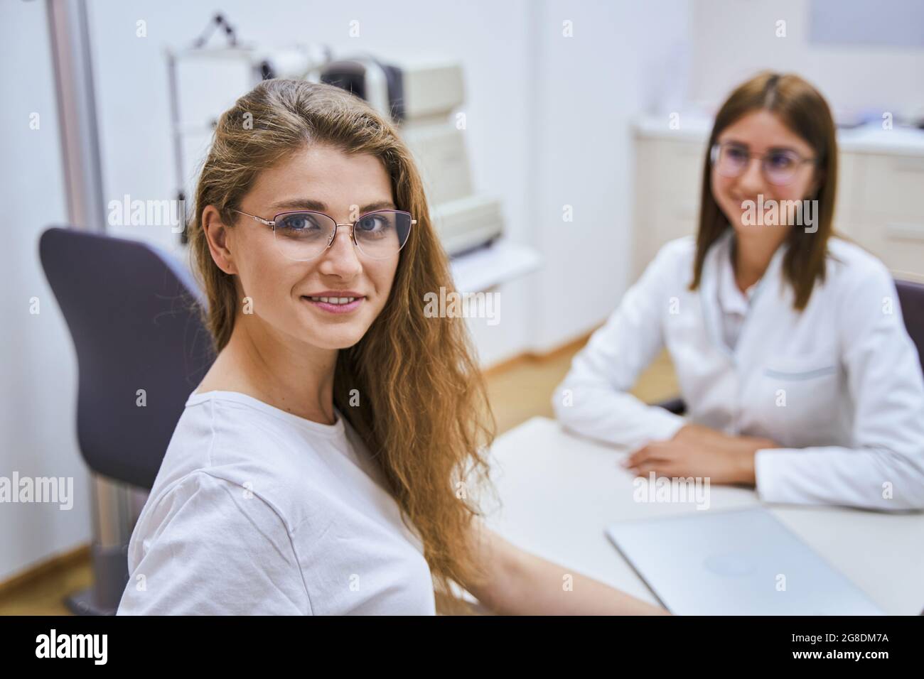Pretty woman in glasses having appointment with optician in clinic ...