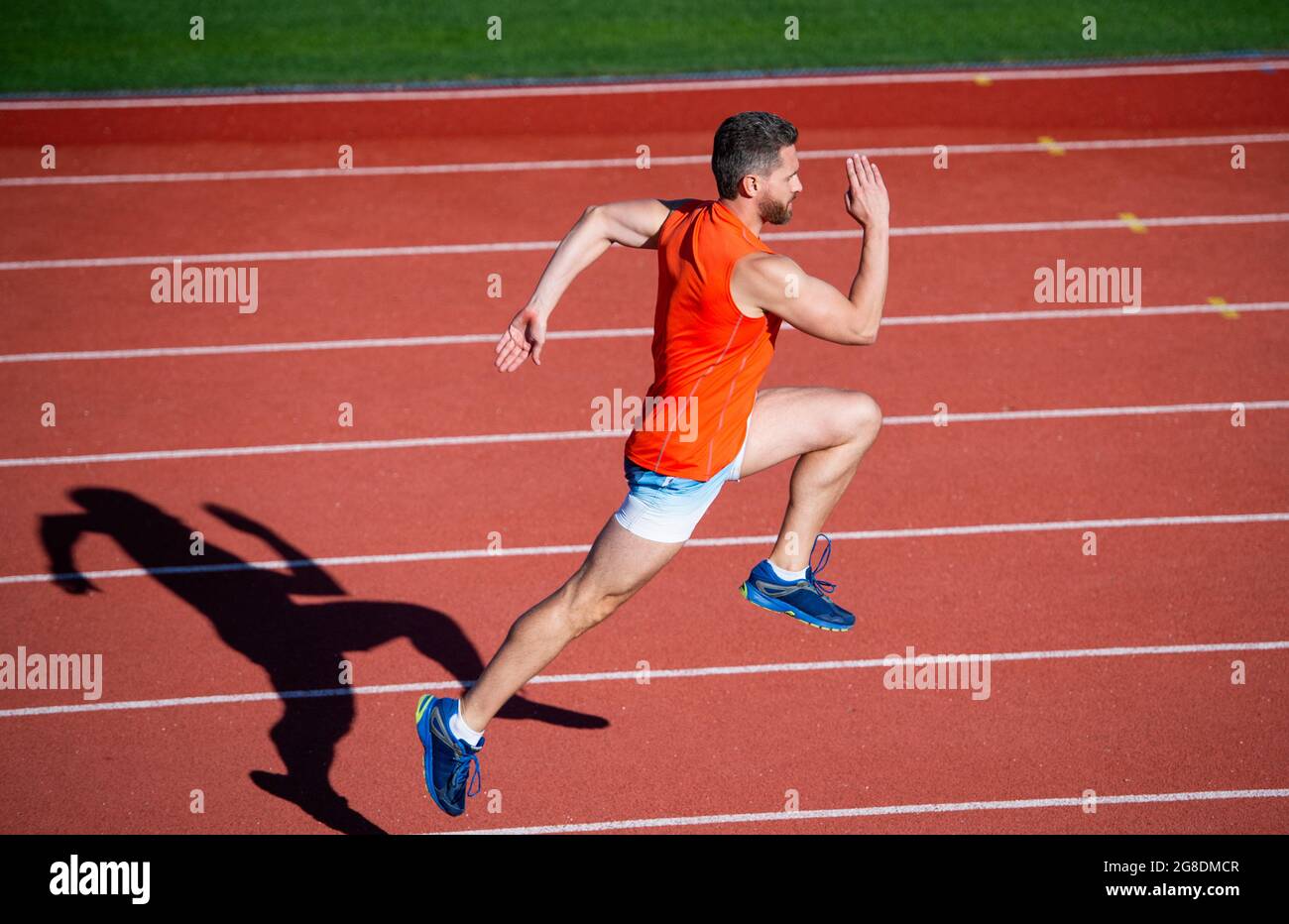 energetic athletic muscular man runner running on racetrack at outdoor ...